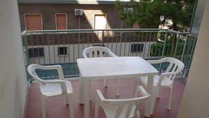 Varanda com mesa branca e quatro cadeiras.