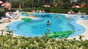 Piscina com várias pistas, rodeada por espreguiçadeiras e guarda-sóis.