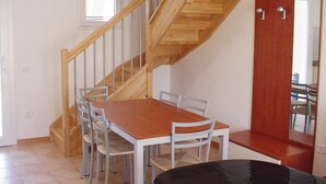 Uma área de refeições com escada de madeira, mesa de jantar com cadeiras e toalha de mesa preta.