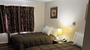 Quarto de hotel com duas camas, uma mesa de cabeceira com abajur, telefone e um quadro na parede.