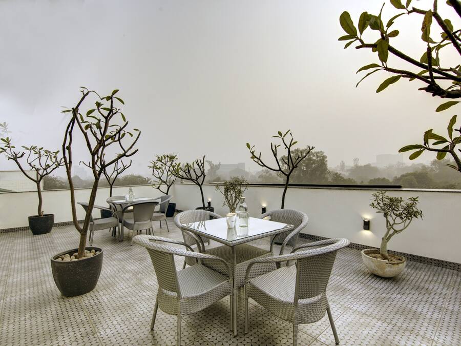 Terraço no telhado com mesa e cadeiras, plantas em vasos e vista para o horizonte urbano.