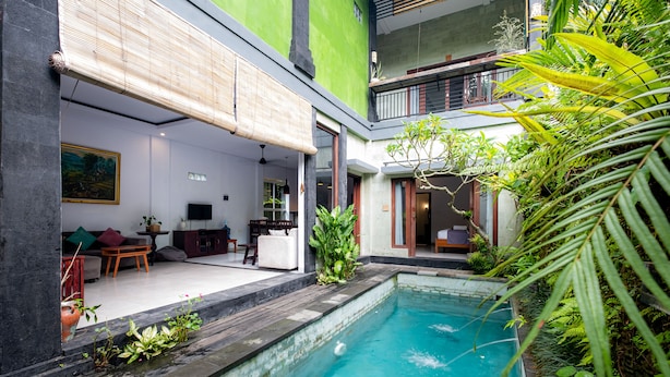 Piscina interior moderna com vista ampla da área circundante, incluindo um espaço de estar com sofá e uma mesa de jantar, além de uma varanda com plantas.