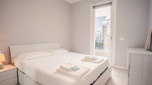 Quarto com cama, mesa de cabeceira, janela e vista para o exterior.