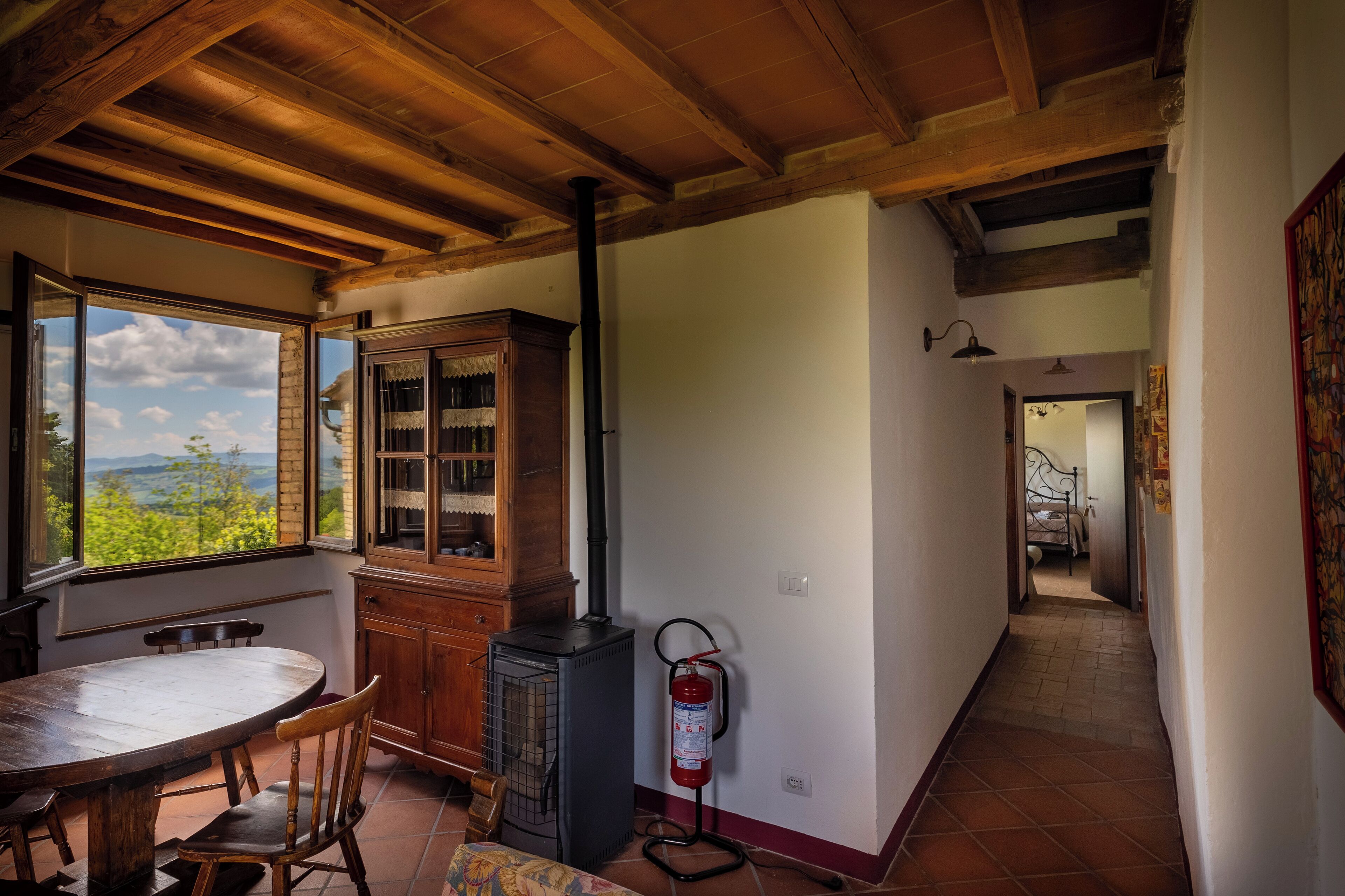 Um interior rústico com uma mesa de madeira, cadeiras, um armário, uma lareira e um extintor de incêndio.