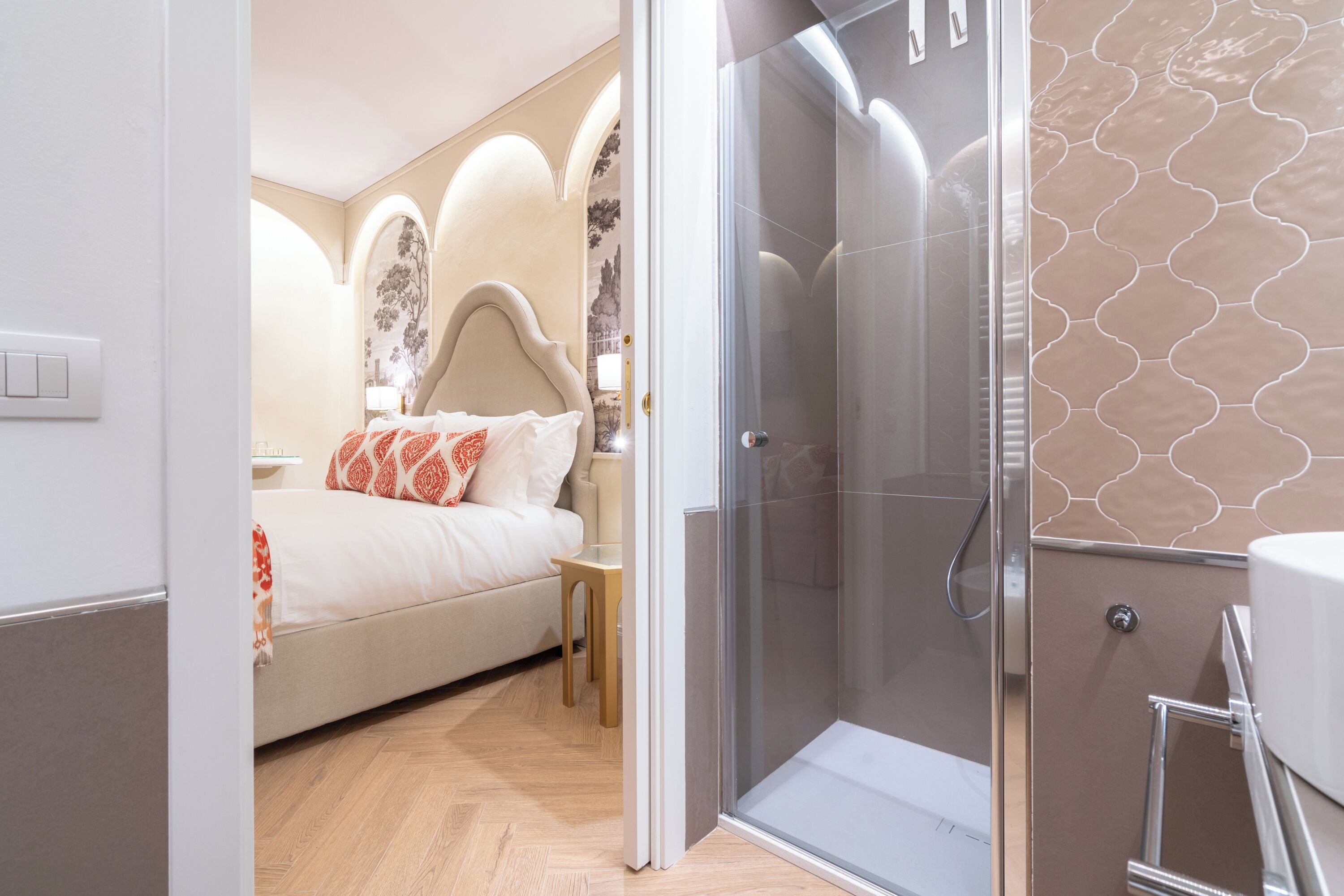 Quarto moderno com cama, mesa de cabeceira e chuveiro em vidro.