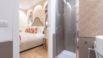 Quarto moderno com cama, mesa de cabeceira e chuveiro em vidro.