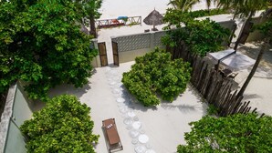 Vista para a praia com piscina, espreguiçadeiras e guarda-sóis.