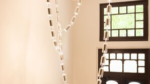 Uma escada com corrimão preto e um candeeiro decorativo suspenso no teto.