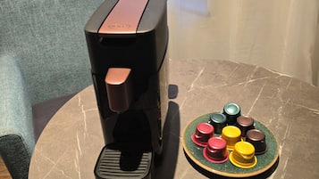 Uma máquina de café sobre uma mesa de mármore com um prato de chávenas coloridas.