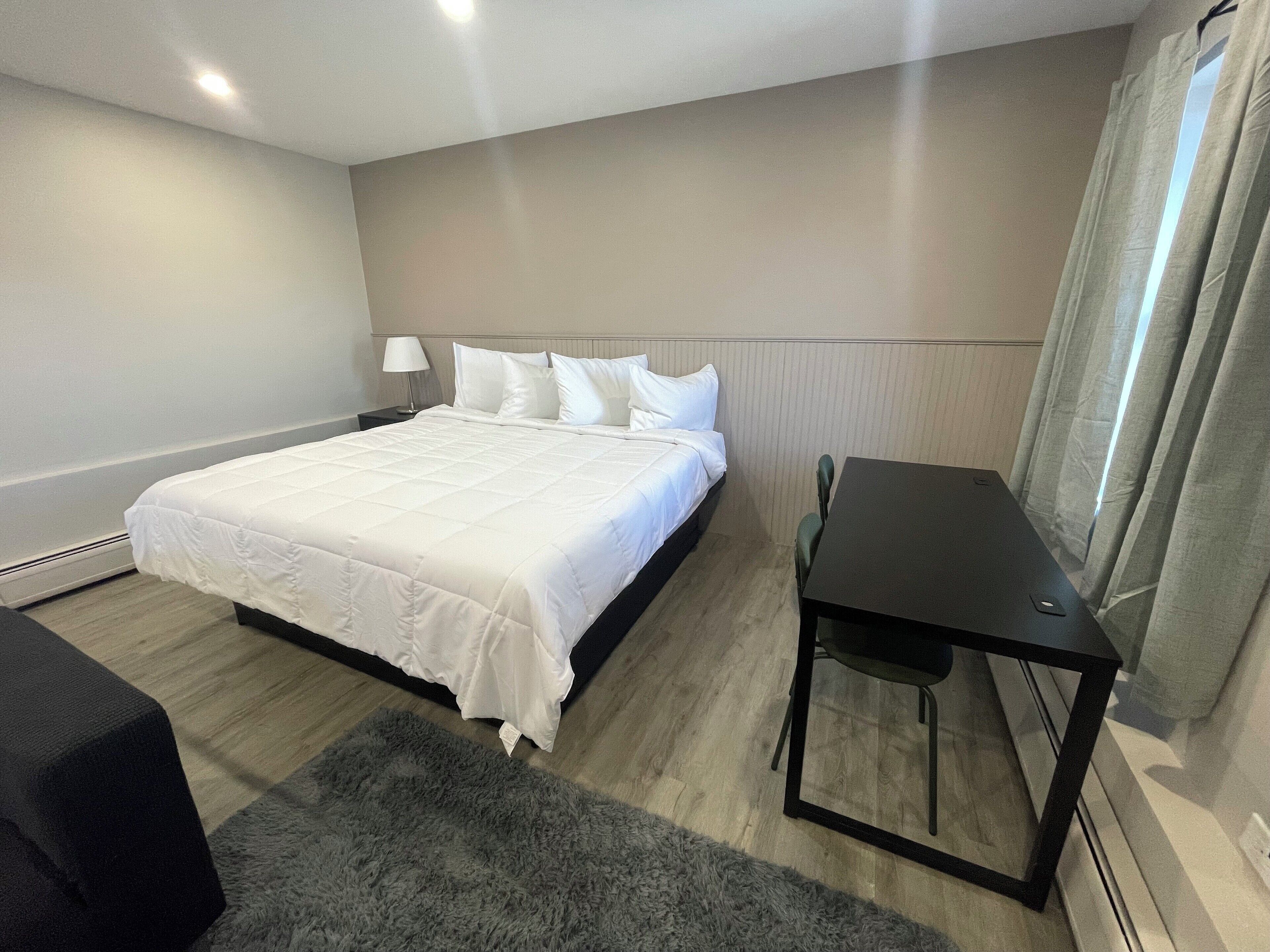 Quarto de hotel bem arrumado com uma cama, uma mesinha e uma cadeira.