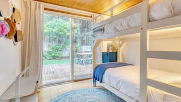 Quarto com beliche e vista para um deck de madeira e uma mesa para piquenique.