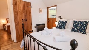 Quarto com cama grande, guarda-roupa de madeira e vista para um jardim pela janela.