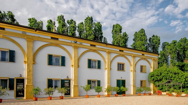 Um edifício com vários arcos e um pátio de cascalho.