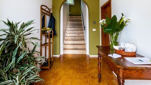 Um corredor com escada de madeira, um banco de madeira e uma mesa com papéis e uma cesta.