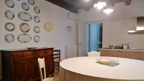 Uma sala de jantar com uma mesa redonda, cadeiras, um armário de madeira e uma parede decorada com pratos.