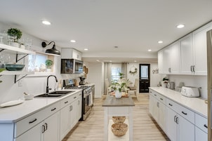 Uma cozinha moderna com armários brancos, uma ilha central e um espaço de refeições com mesa e cadeiras.