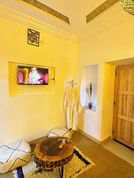 Quarto com televisão na parede, uma mesa de madeira, roupão e porta de madeira.