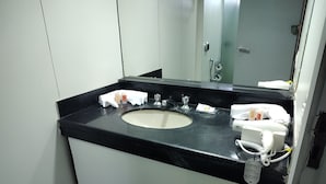 Casa de banho com lavatório, espelho e artigos de higiene pessoal.