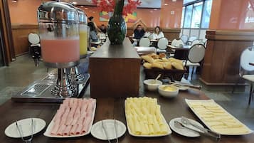 Disposição de buffet com diversos alimentos e um distribuidor de bebidas.