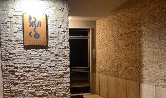 Pared de tijolos com uma placa indicando 'Bri' e 'Quartos e Suítes'.