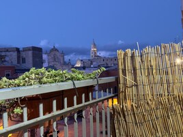 Varanda com vista para um edifício histórico e uma cerca de bambu.
