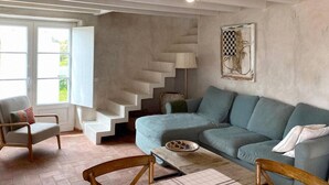 Uma sala de estar moderna com um sofá azul claro, uma mesa de centro de madeira, uma escada em espiral e uma janela grande.