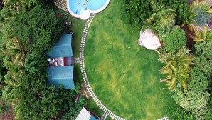 Vista aérea de uma piscina cercada por vegetação exuberante e palmeiras.