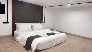 Quarto com cama, cabeceira, mesa de cabeceira e abajur.
