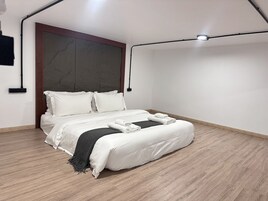 Quarto com cama, cabeceira, mesa de cabeceira e abajur.