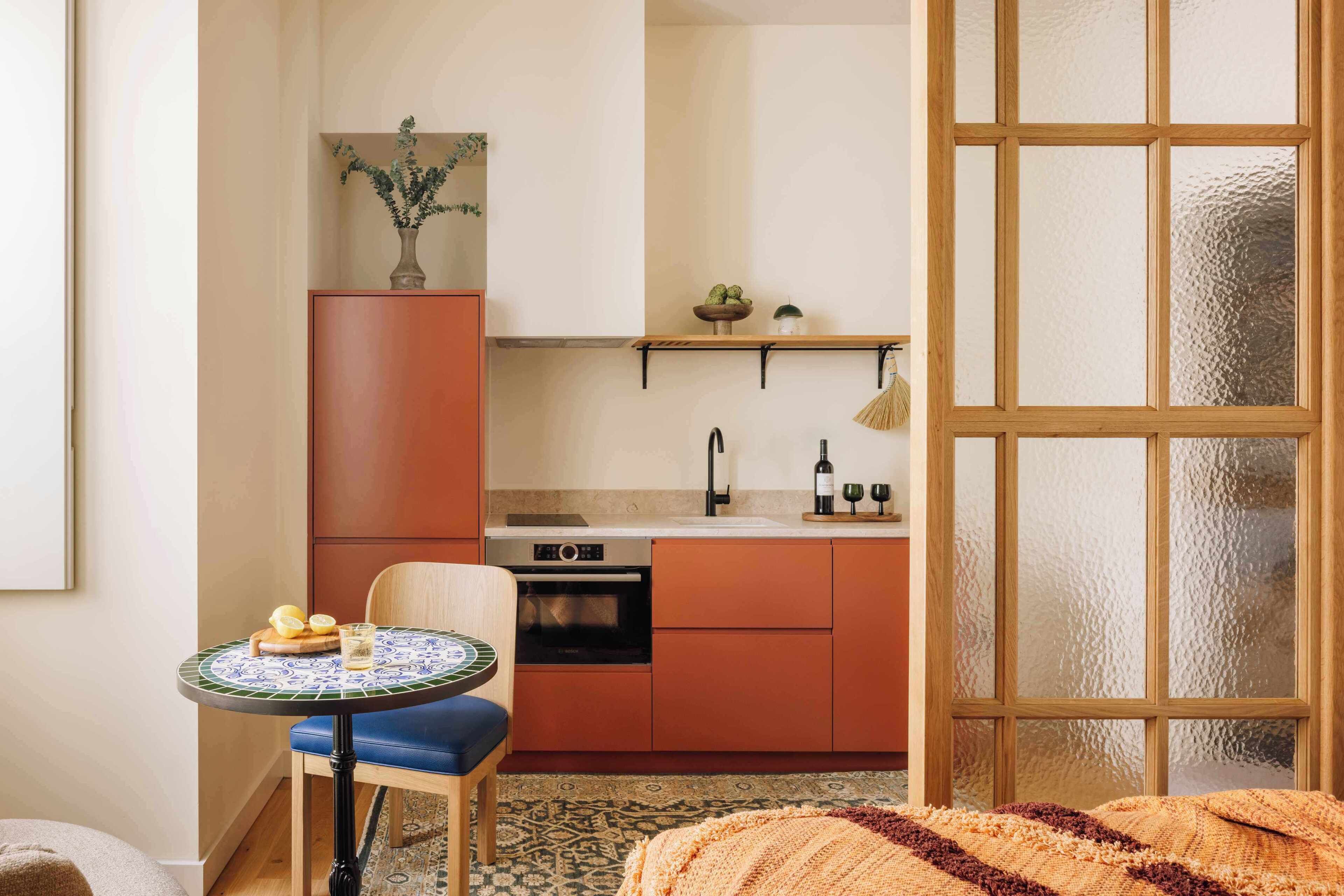 Uma cozinha compacta com área de refeições, com uma mesa pequena, uma cadeira e um armário.