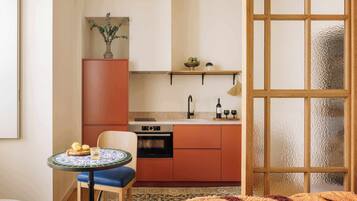 Uma cozinha compacta com área de refeições, com uma mesa pequena, uma cadeira e um armário.