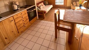Uma cozinha acolhedora em estilo cabana, com armários de madeira, piso ladrilhado, mesa de jantar com cadeiras e um sofá.