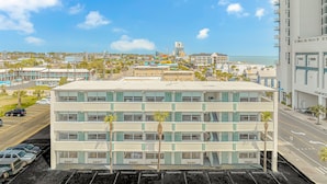 Um hotel de vários andares com estacionamento em frente, vista desimpedida da praia e uma roda gigante ao longe.
