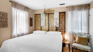 Quarto com uma cama grande, uma cadeira e uma parede com painéis decorativos.