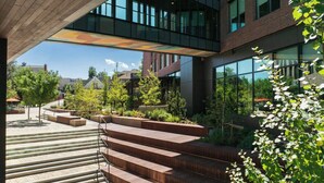 Um edifício moderno com fachada de vidro, escadas externas e vegetação.