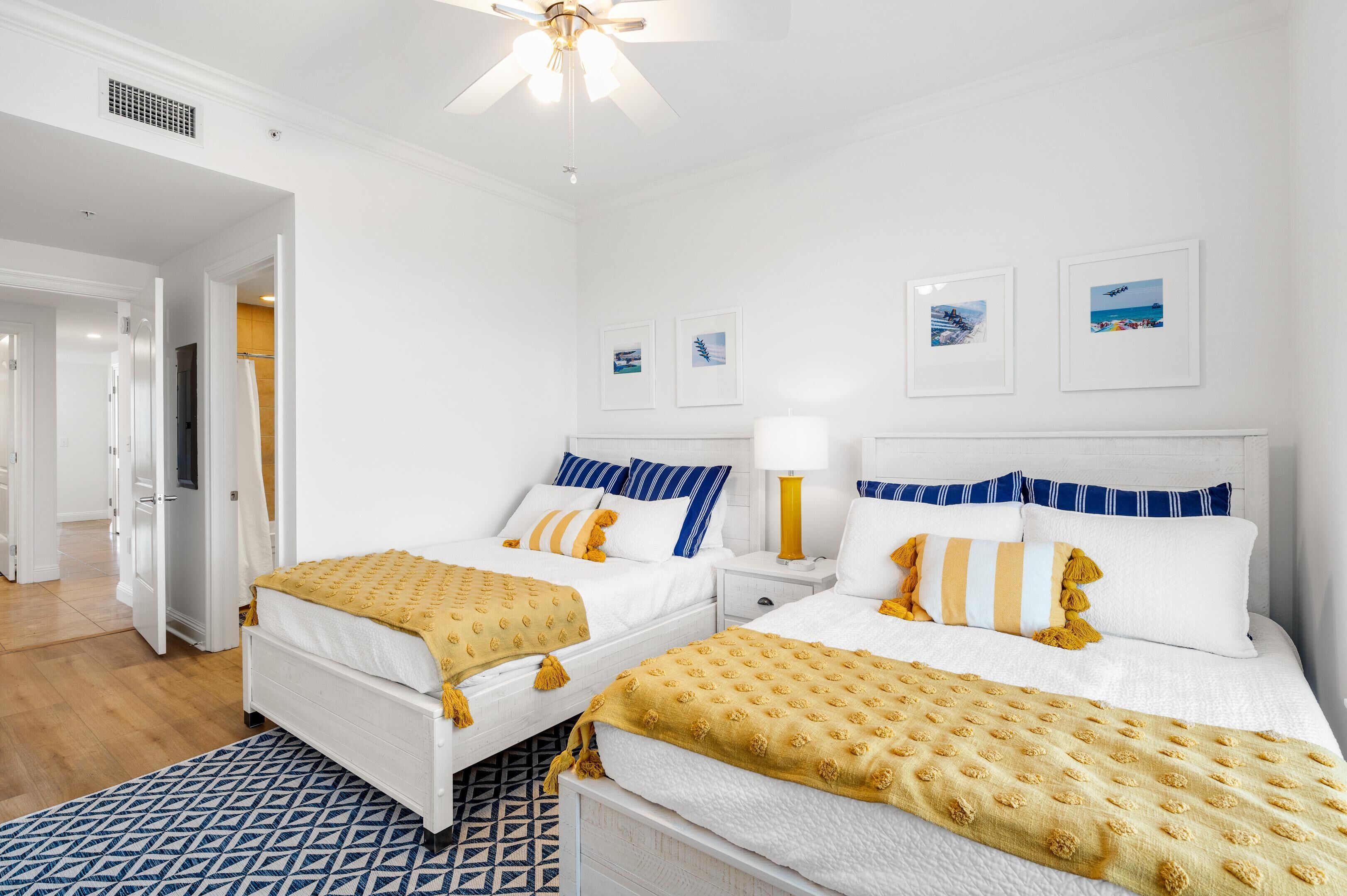 Quarto de hotel com duas camas, paredes brancas e um tapete estampado.