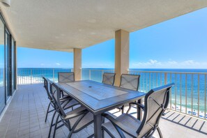 Varanda com mesa e cadeiras, vista para a praia e oceano.