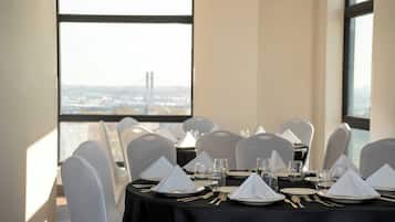 Uma sala de conferências com uma mesa posta para uma reunião, cadeiras dispostas ao redor e uma grande janela com vista para a cidade.