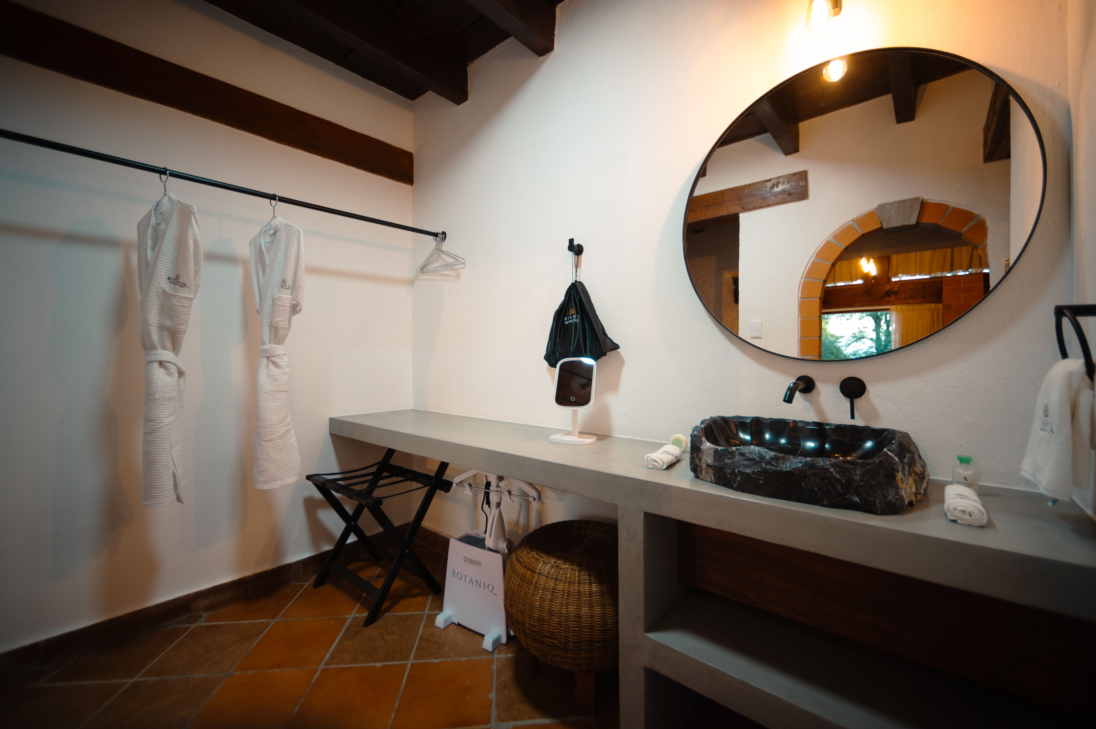 Casa de banho com um espelho grande, uma pia com cuba de pedra e duas toalhas penduradas num porta-toalhas.