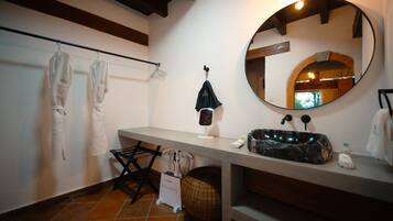 Casa de banho com um espelho grande, uma pia com cuba de pedra e duas toalhas penduradas num porta-toalhas.