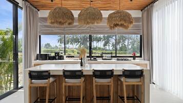 Cozinha moderna com uma ilha grande, banquetas e vista para palmeiras.