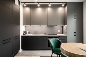 Uma cozinha moderna com armários escuros, uma mesa de madeira redonda e uma cadeira verde.