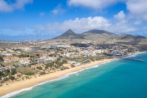 Uma cidade costeira com praia, montanha e um píer.