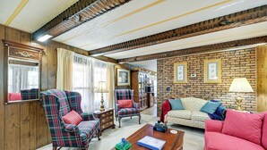 Uma sala de estar tradicional com painéis de madeira, parede de tijolos e móveis clássicos.