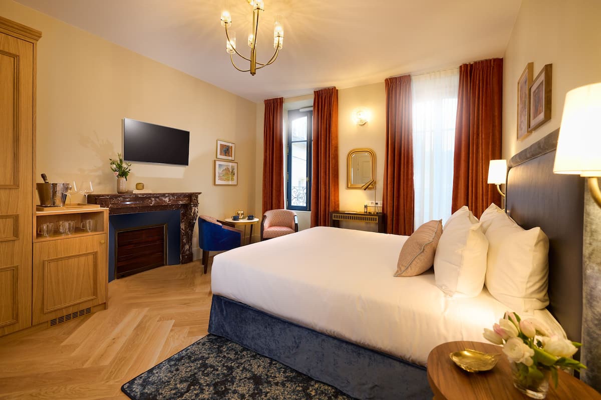 Quarto de hotel com uma cama grande, televisão de tela plana, lareira, escrivaninha e vista para o exterior.