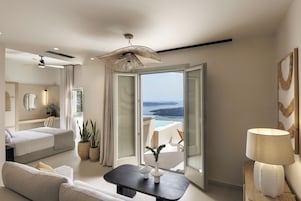 Quarto de hotel moderno com varanda, cama, sofá, mesa e luminária.