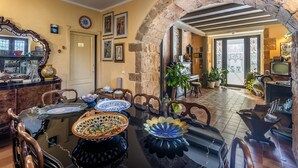 Uma área de refeições com um arco de pedra, uma mesa de jantar com diversos pratos e uma televisão ao fundo.