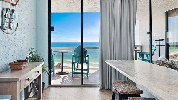 Varanda com vista para o oceano, uma mesa, cadeiras e um banco de vime.