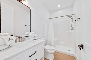 Uma casa de banho moderna com lavatório branco, sanita e zona de duche.
