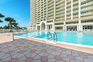 Um hotel grande com piscina, várias varandas e um caminho de ladrilho.